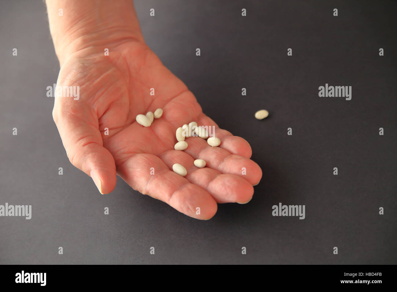 A man holds small white beans in his hand on a dark background Stock ...