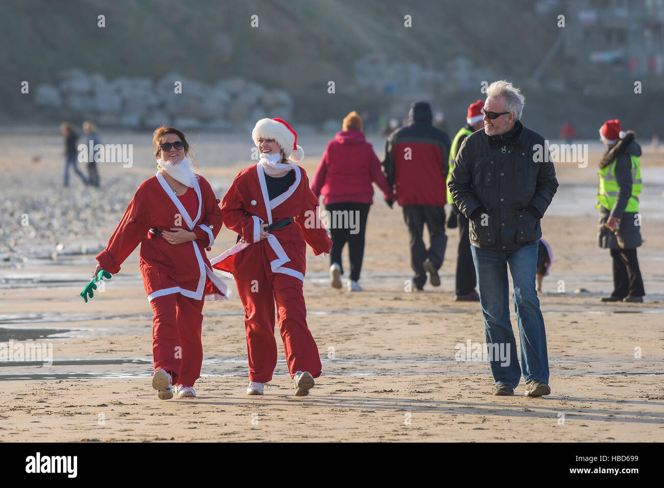 Two women dressed as Santas walking across Fistral Beach to the start ...