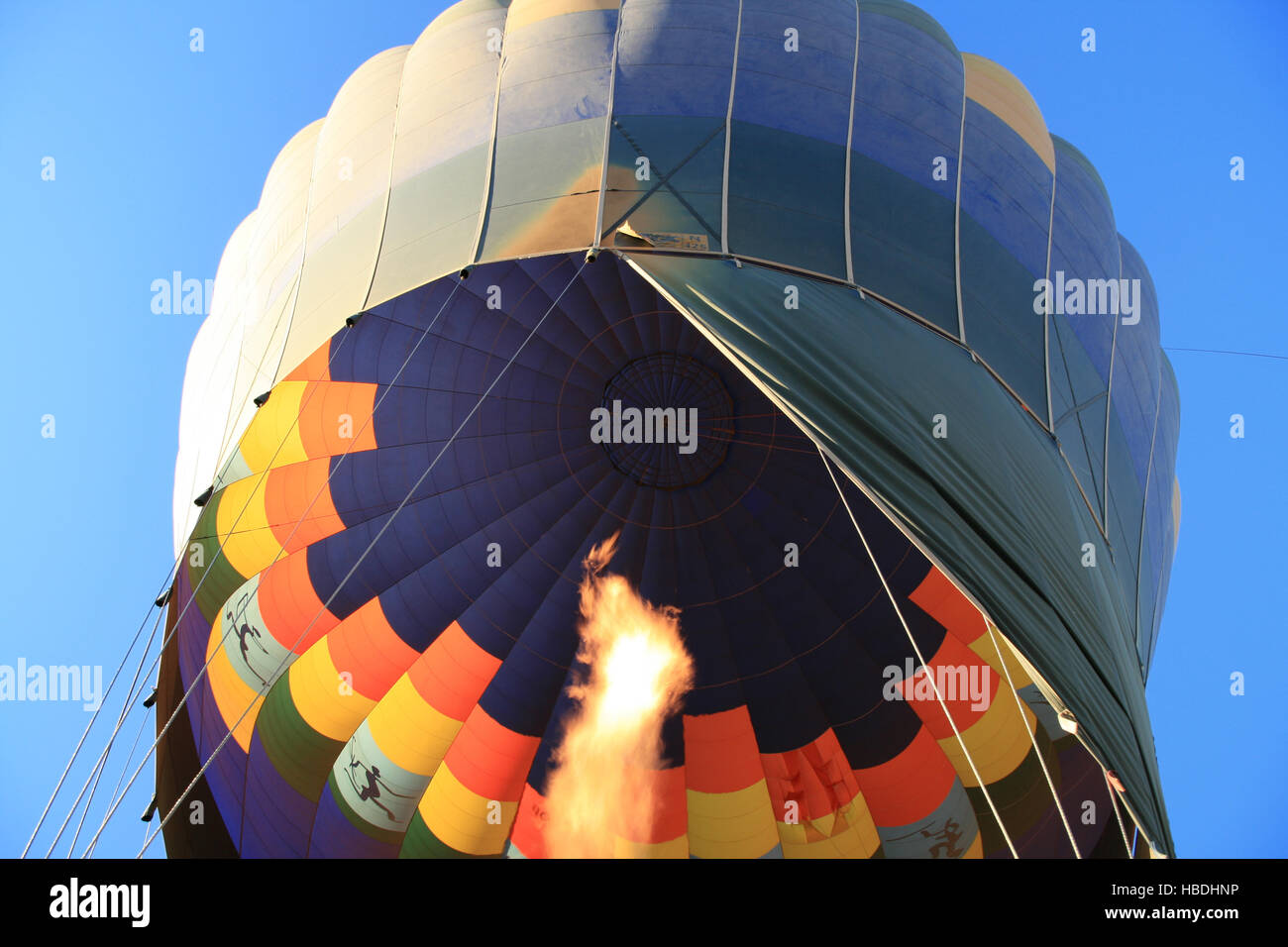 Flame warming a hot air balloon as it rises into a clear blue sky Stock ...