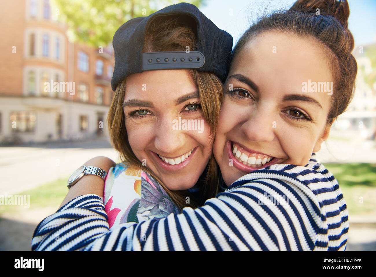 Two happy young girls in an intimate hug looking at the camera with ...