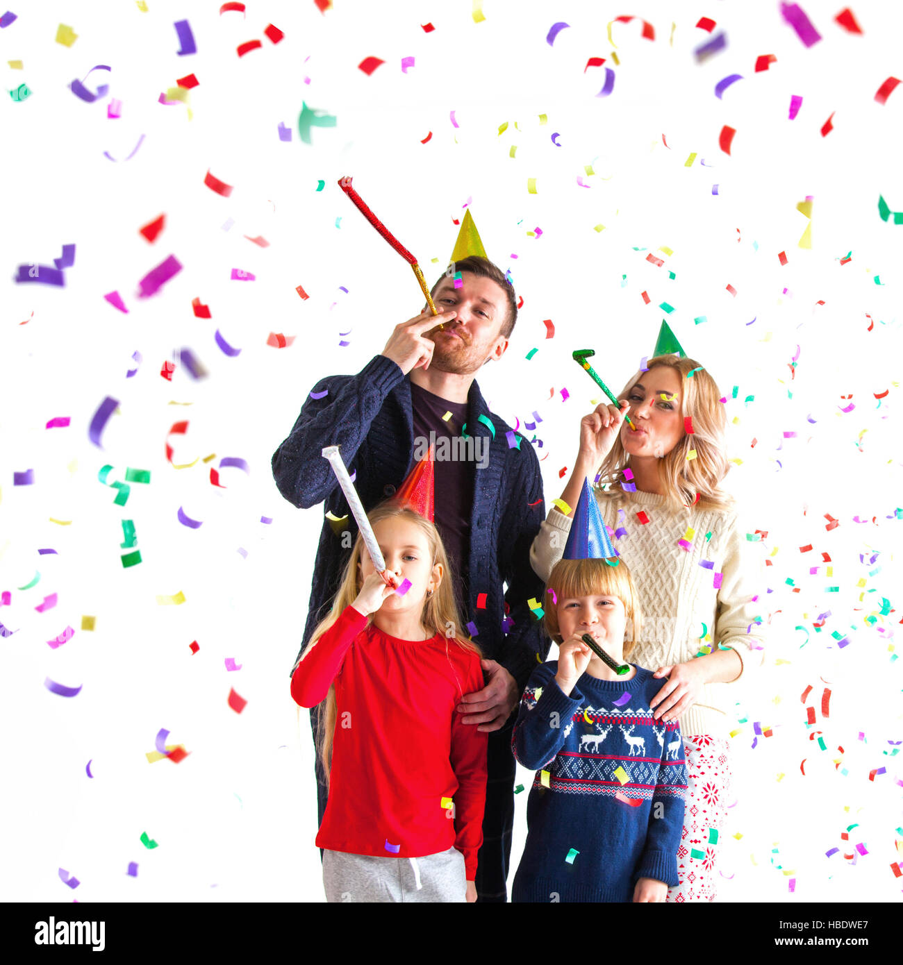 Family blowing party trumpets with confetti celebrating new year Stock ...