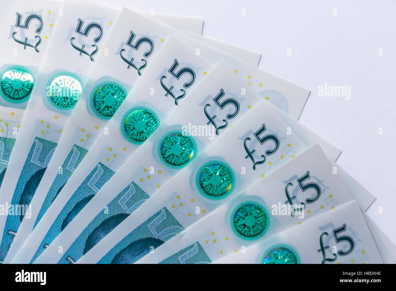 Eight new 5 pound notes set out in a fan array on a white background ...
