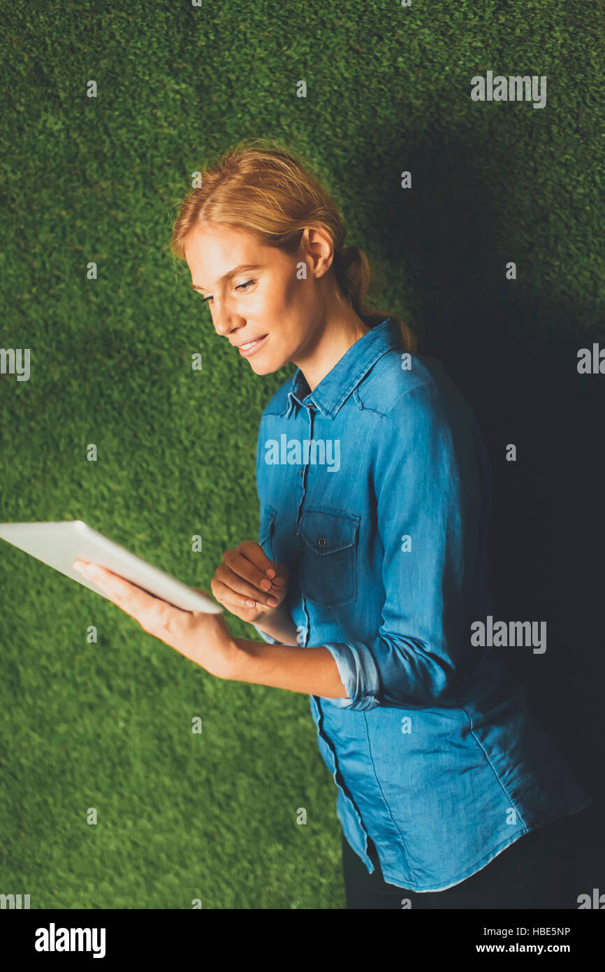 Young woman posing with tablet by green wall Stock Photo - Alamy