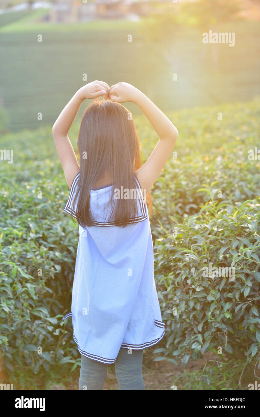 Asian girl making a heart shape with arms on the backside , outdoor ...