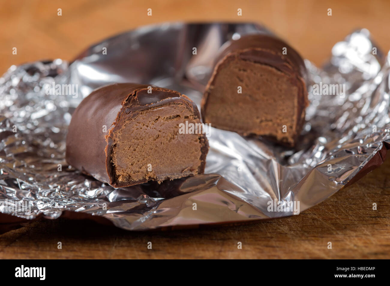 Cross section of one chocolate candy on silver foil over wooden ...