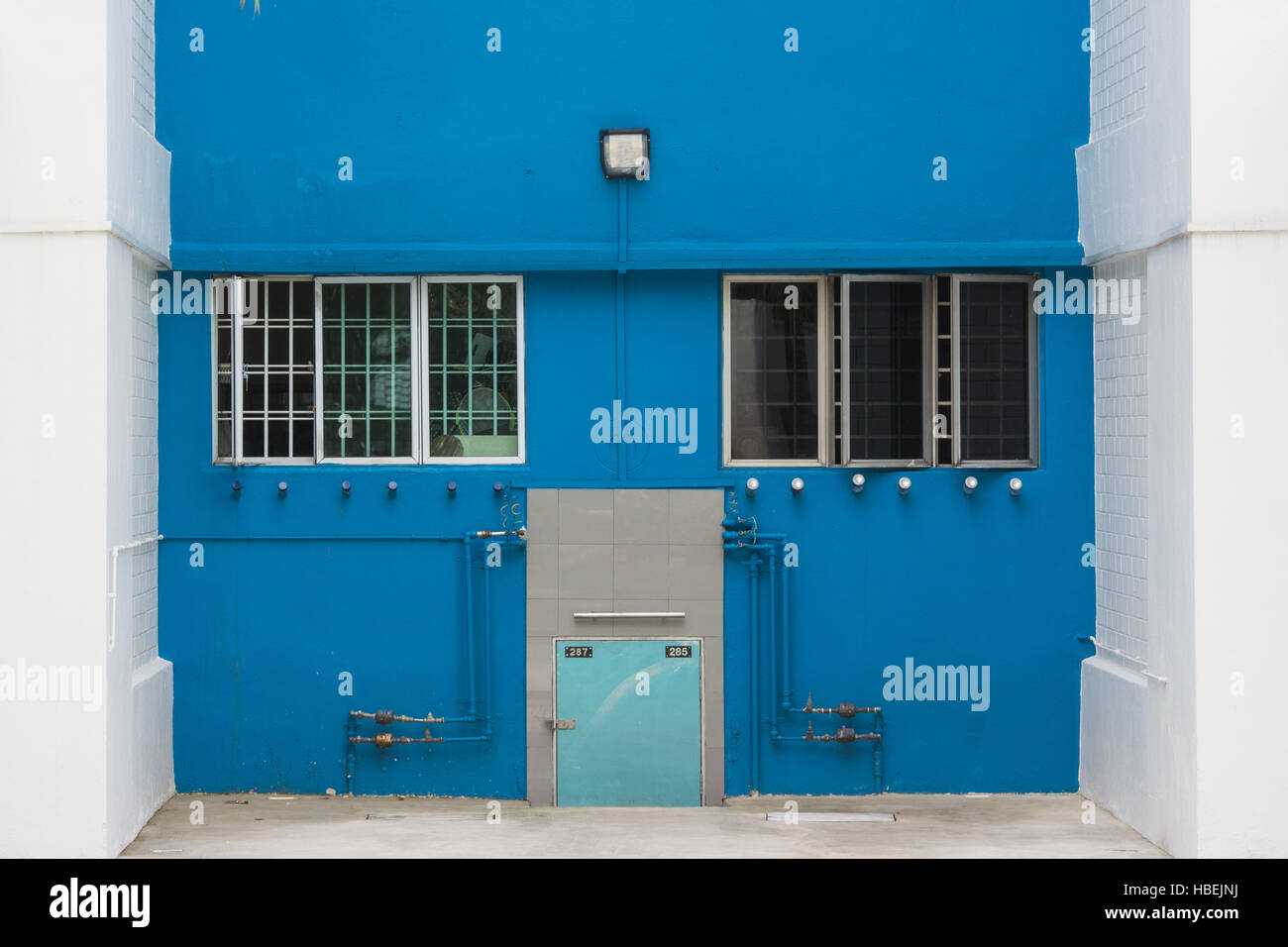 Blue wall with windows and a trash collection area, surrounded by white ...