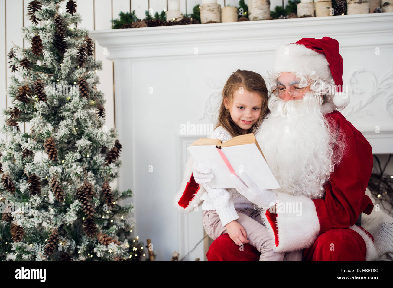 happy child girl hugging Santa reading book and laughs Stock Photo - Alamy