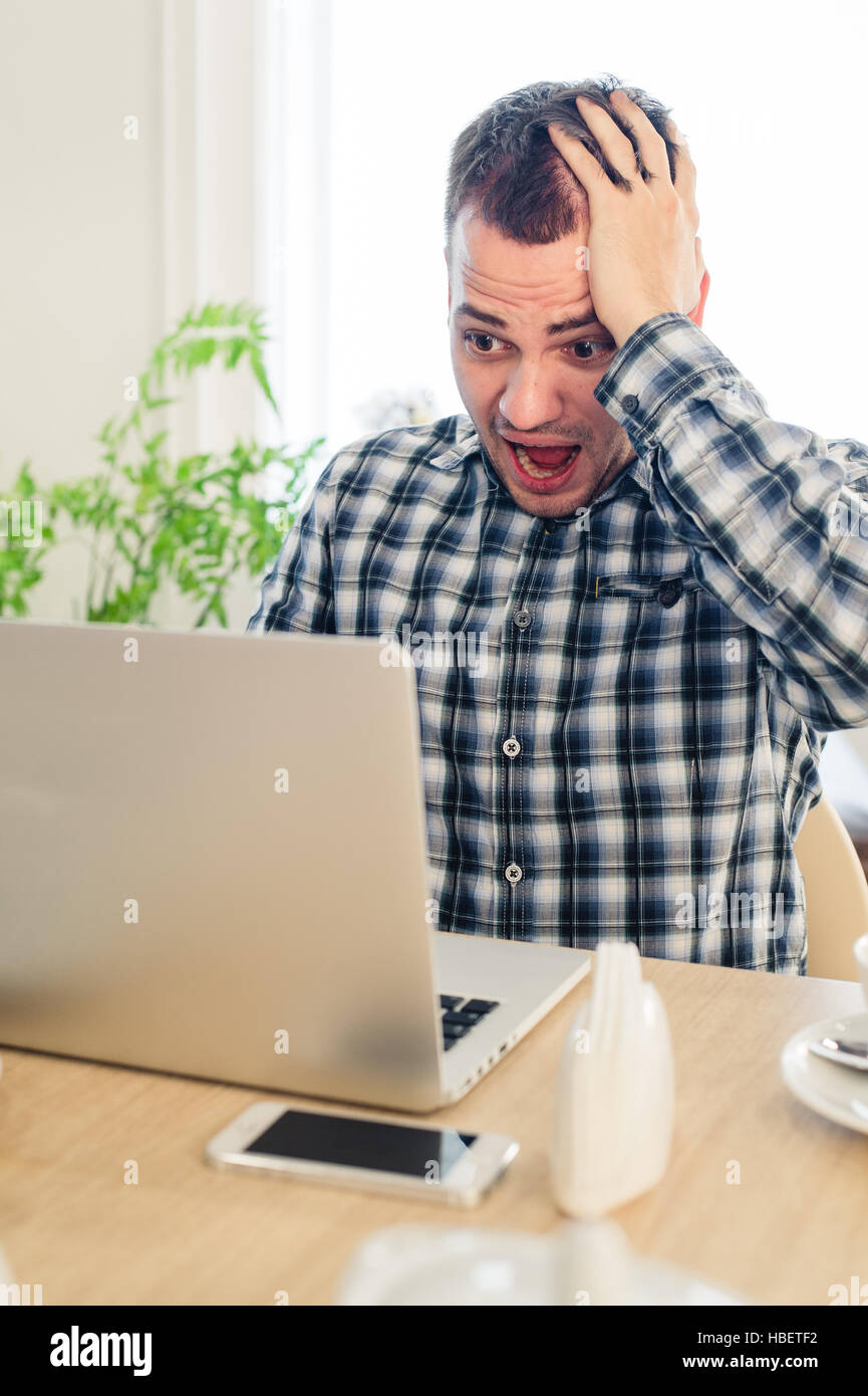 Worried shoked man looking on laptop at cafe Stock Photo - Alamy