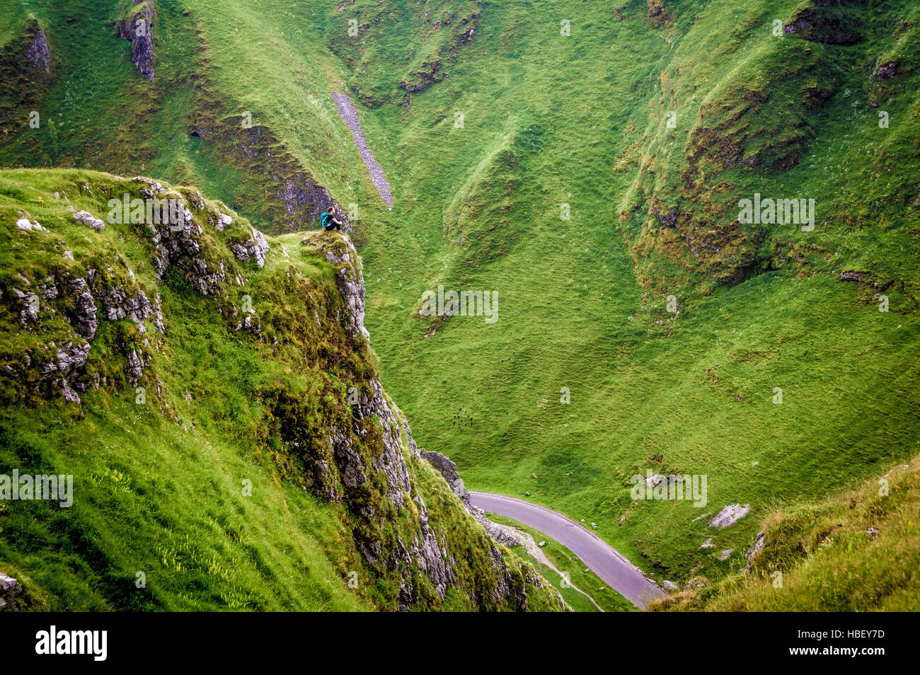 Female on rocky outcrop with road below, Peak District, Derbyshire, UK ...
