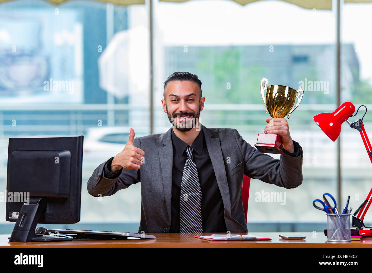 Businessman winning cup trophy in the office Stock Photo - Alamy