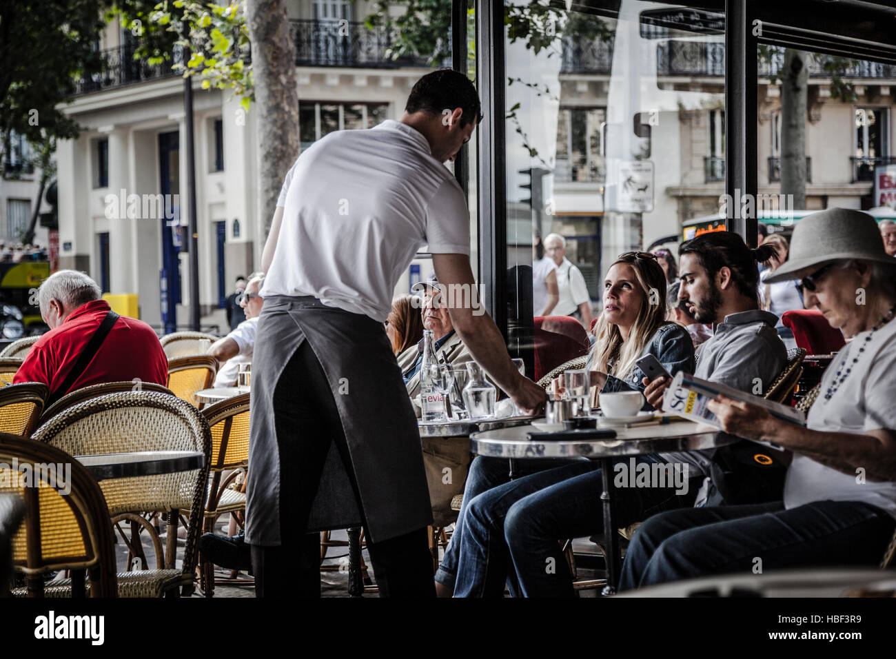 Waiter serving customers at traditional outdoor Parisian cafe in center ...