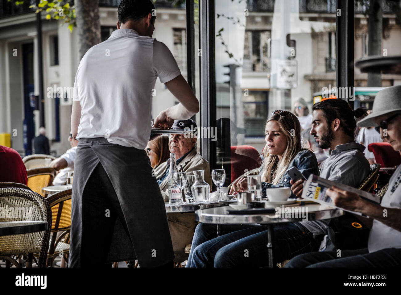 Waiter serving customers at traditional outdoor Parisian cafe in center ...