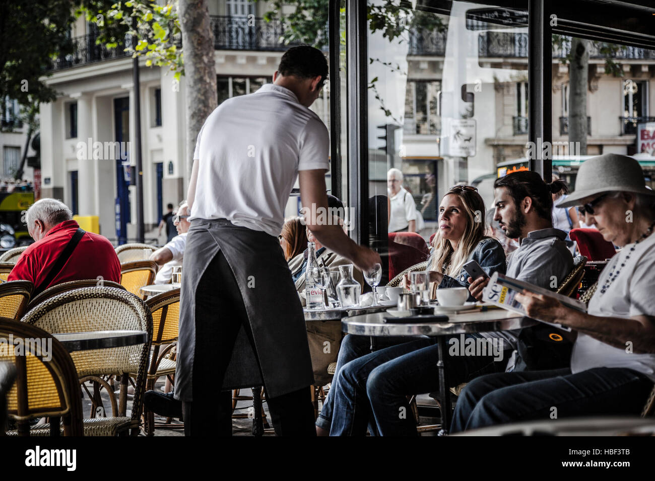 Waiter serving customers at traditional outdoor Parisian cafe in center ...