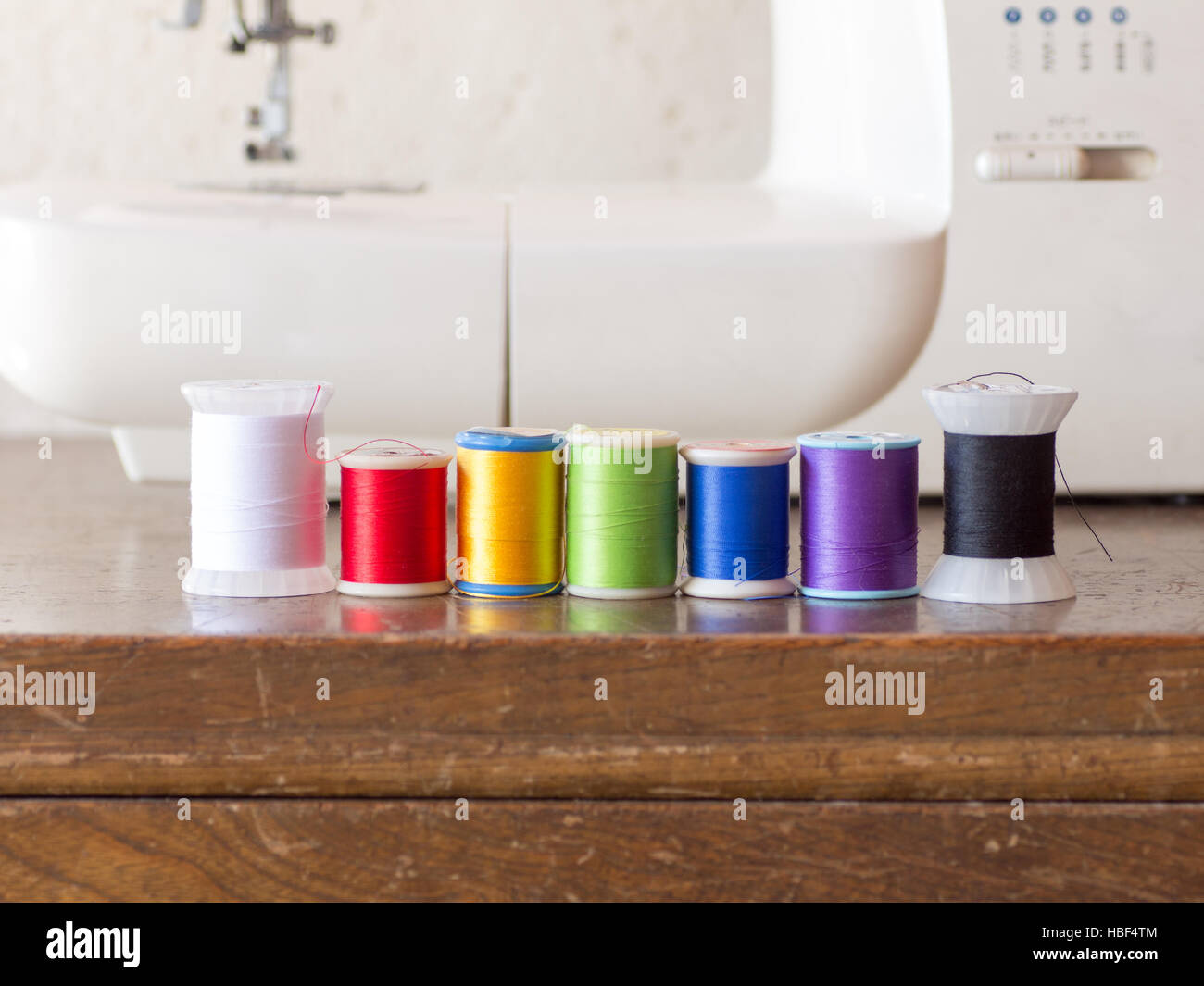 Sewing machine and its colorful threads on wooden table Stock Photo - Alamy