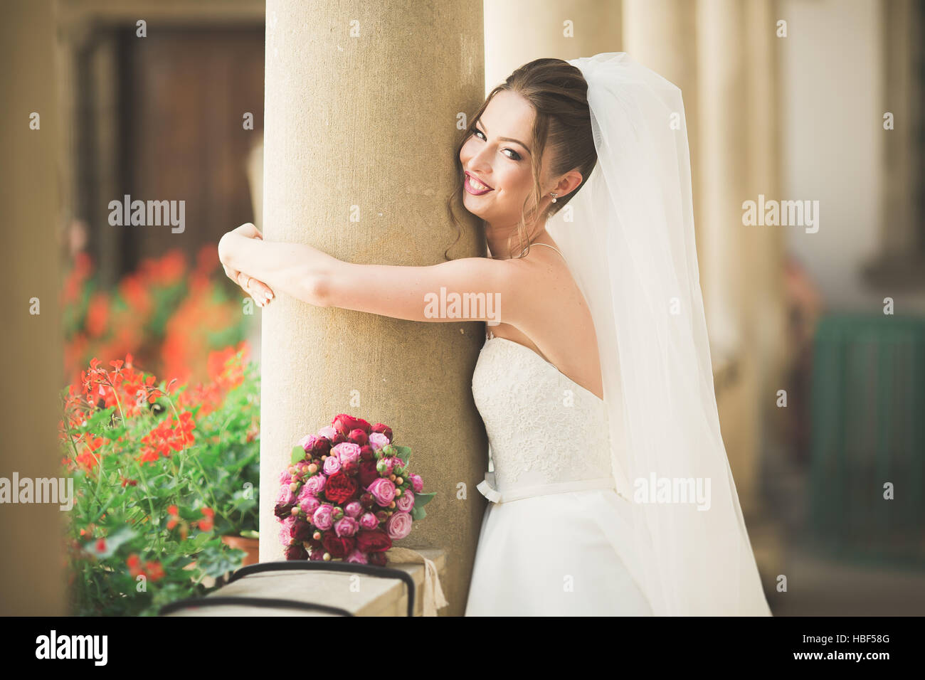 Wonderful bride with a luxurious white dress posing in the old town ...