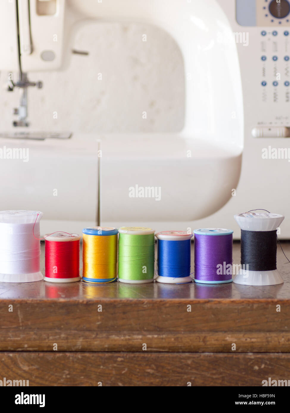 Sewing machine and its colorful threads on wooden table Stock Photo - Alamy