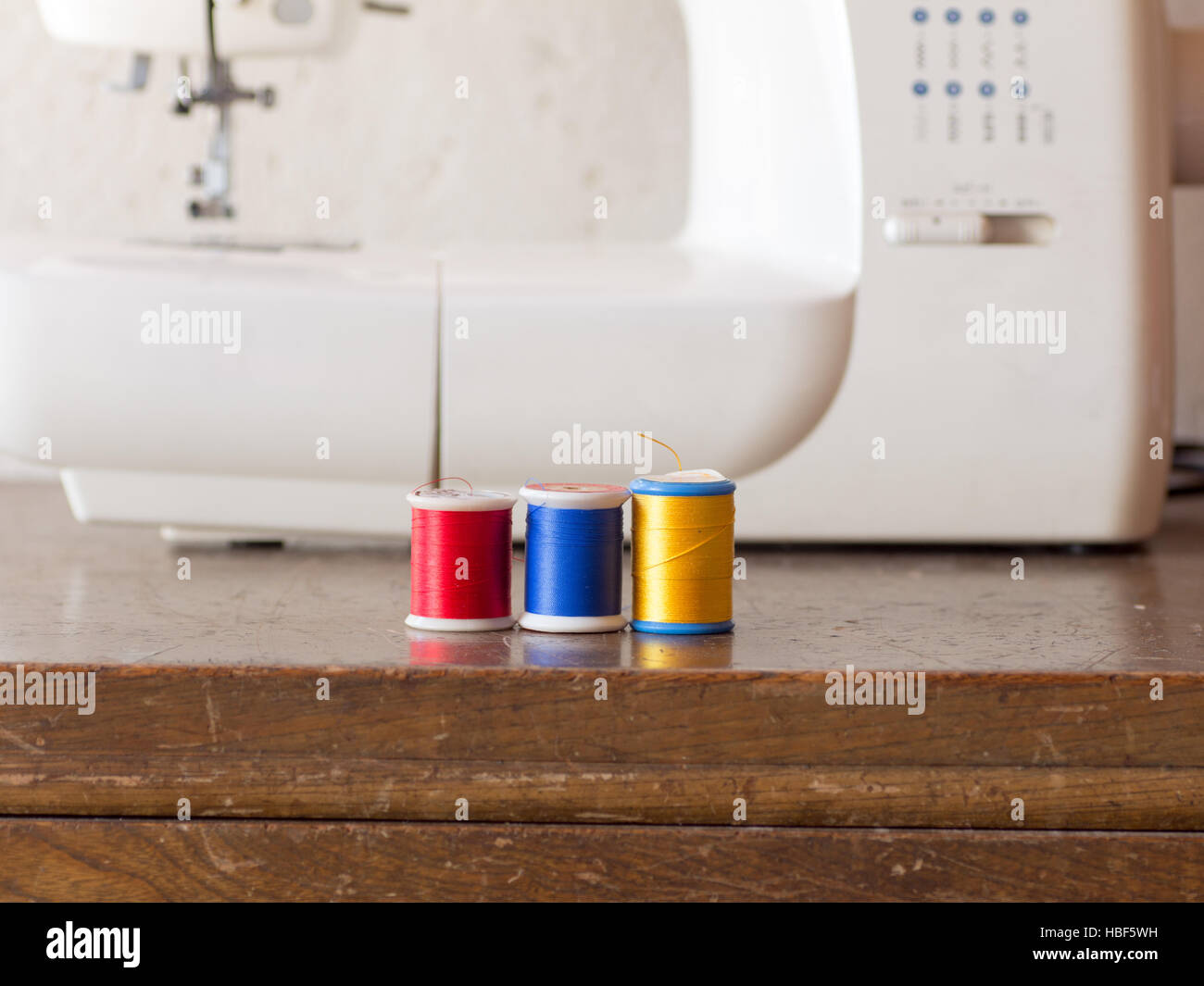 Sewing machine and its colorful threads on wooden table Stock Photo - Alamy