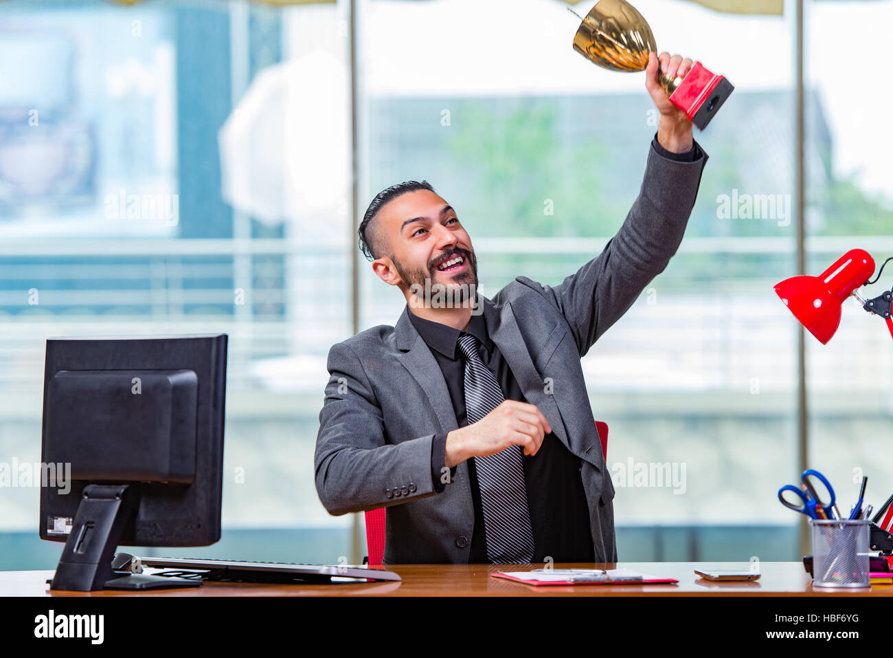 Businessman winning cup trophy in the office Stock Photo - Alamy