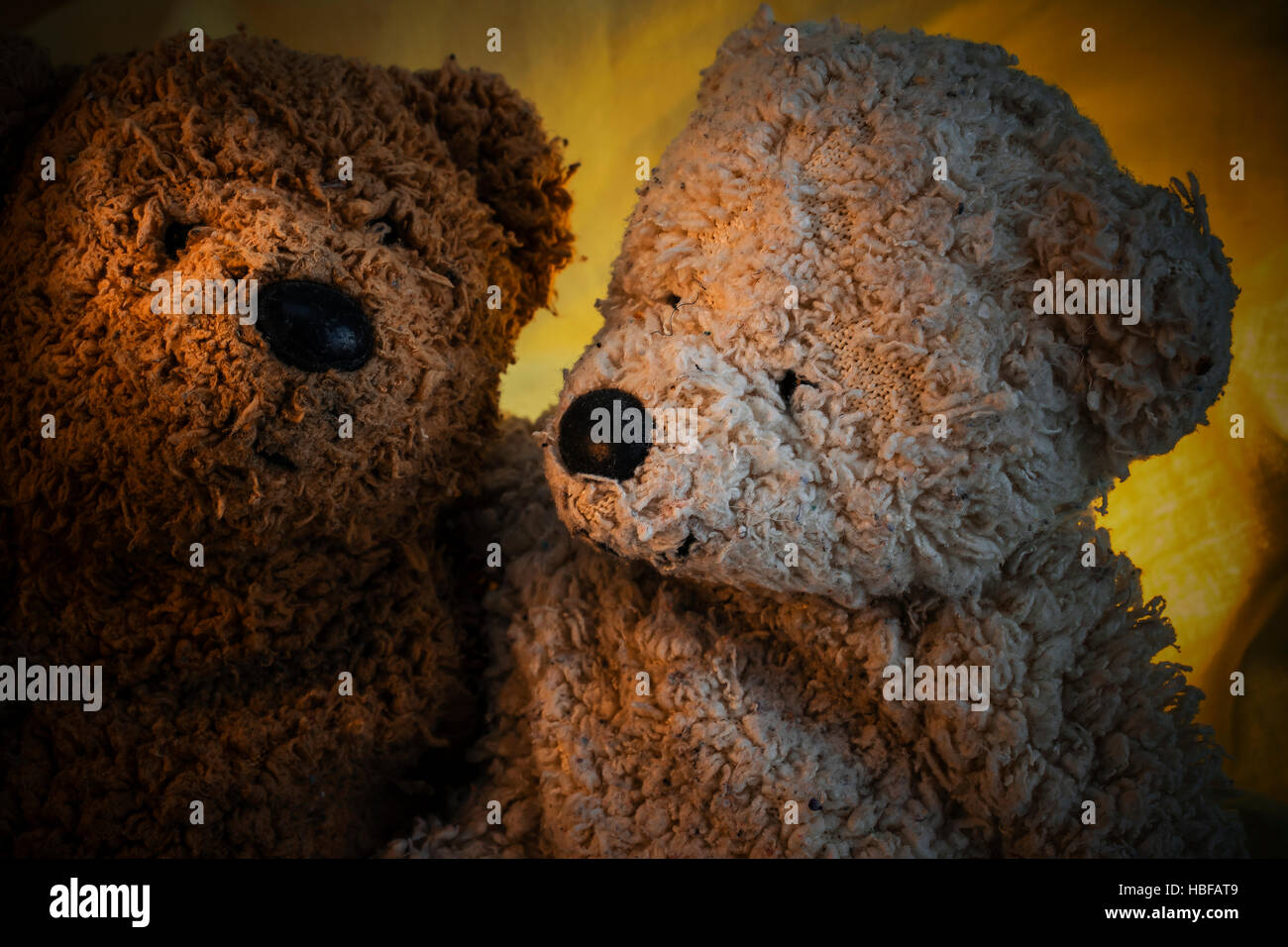 Two Teddy Bears sit embracing one another. One is smiling and the other ...