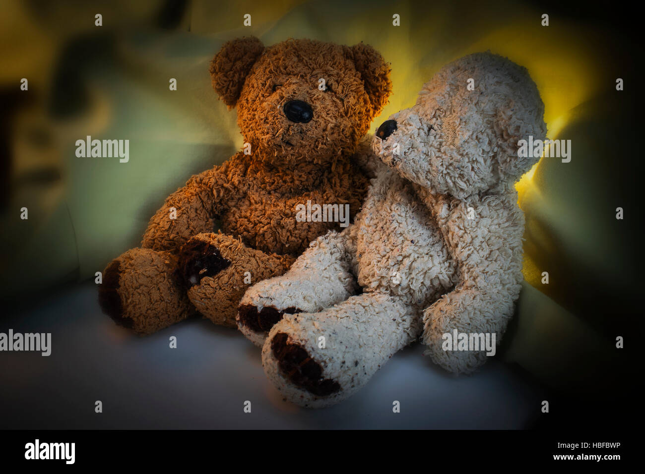 Two Teddy Bears sit embracing one another. One is smiling and the other ...
