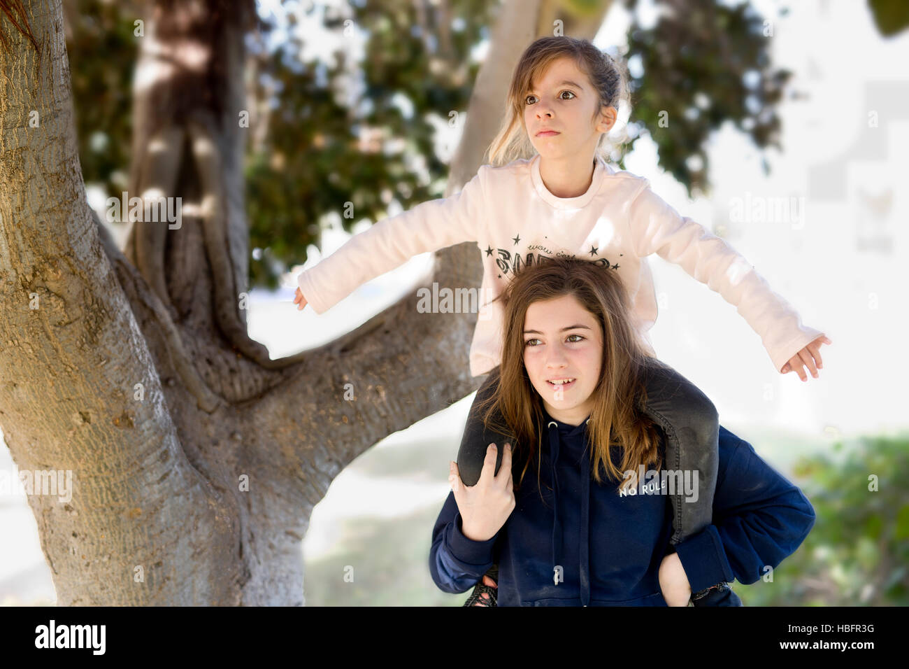 Girl climb on the shoulders of his sister, making games a sunny autumn ...
