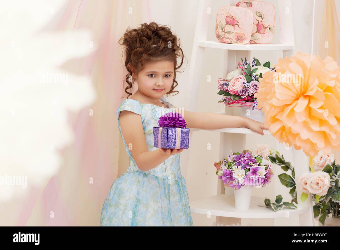 Cute girl posing with gift box in decorated studio Stock Photo - Alamy