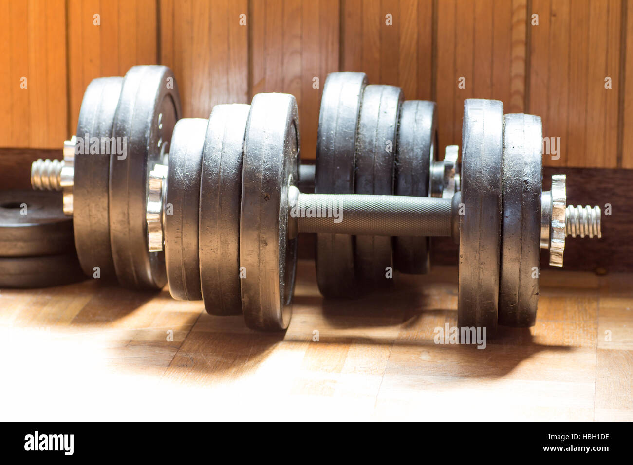 A shiny pair of rubber dumbbell on wooden floor Stock Photo - Alamy