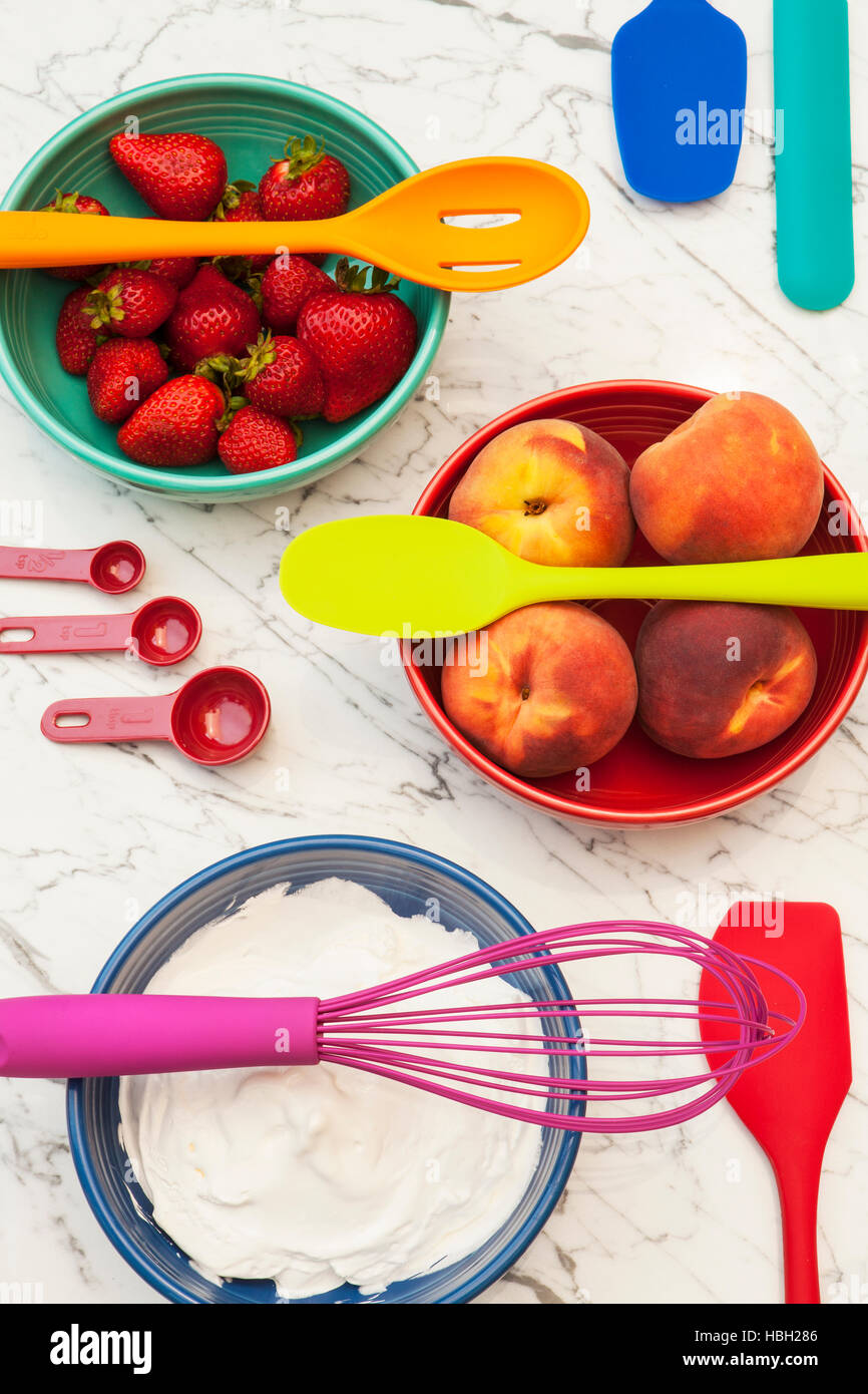 colorful kitchenware and bowls with strawberries, peaches and cream ...