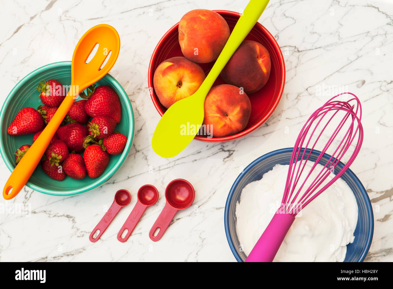 colorful kitchenware and bowls with strawberries, peaches and cream ...