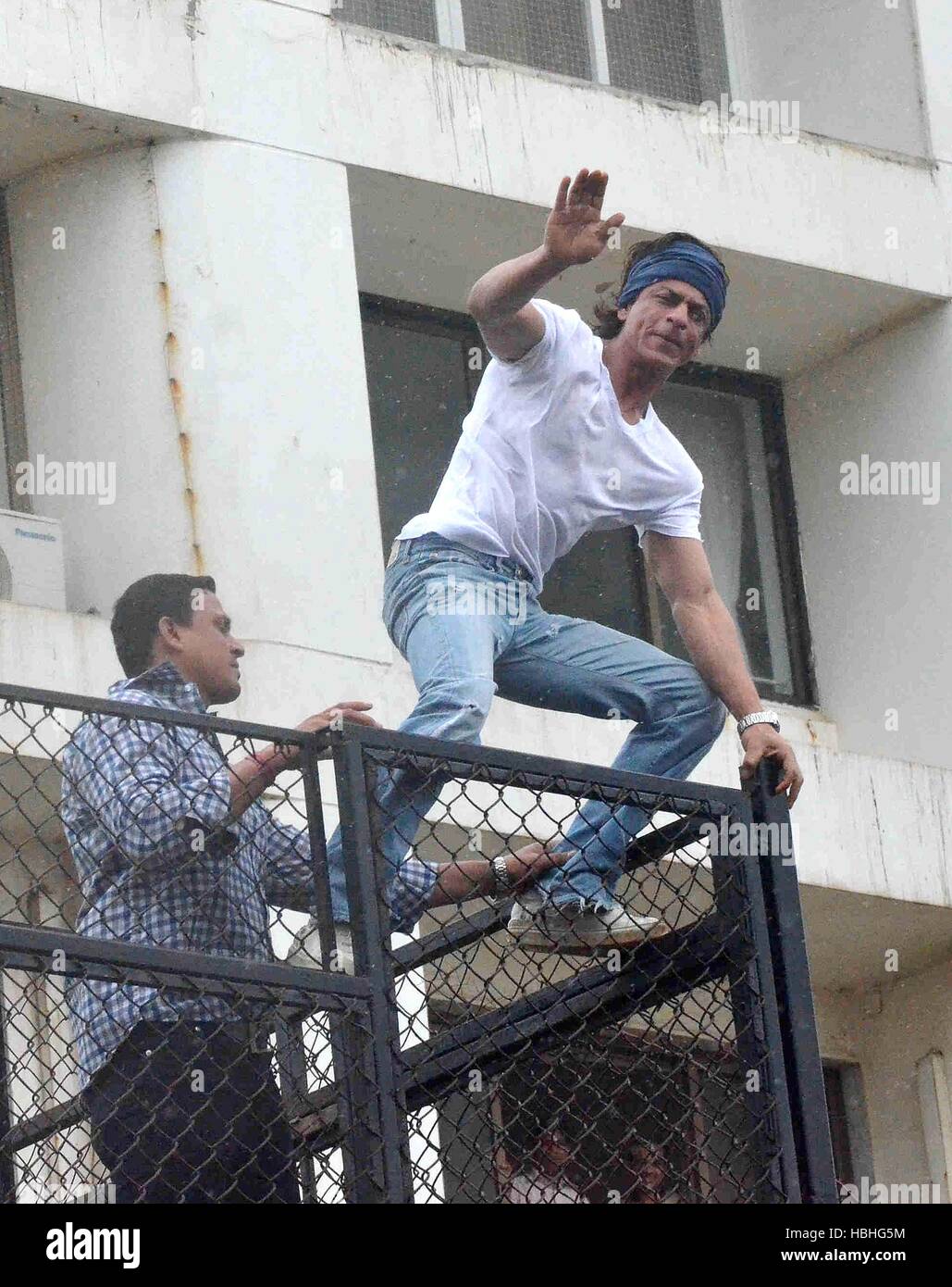 Shah Rukh Khan waving to crowd from above balcony fence to people below ...