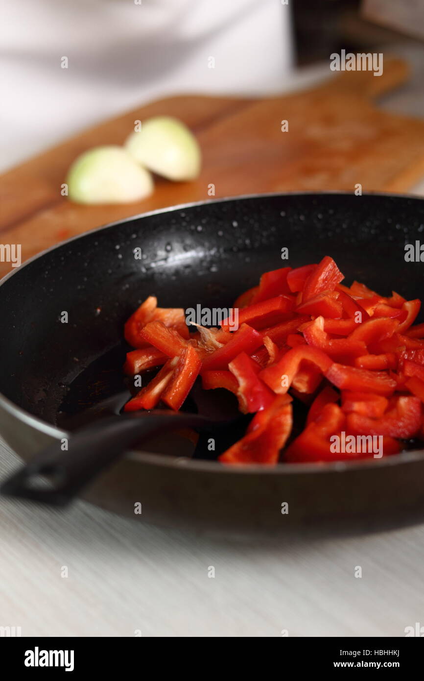 Sliced raw red bell pepper in frying pan. Making Chicken and Egg ...