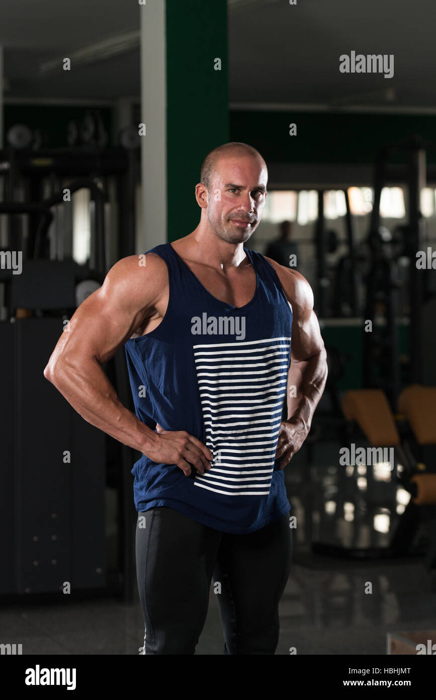 Young Bald Man Standing Strong In The Gym And Flexing Muscles ...