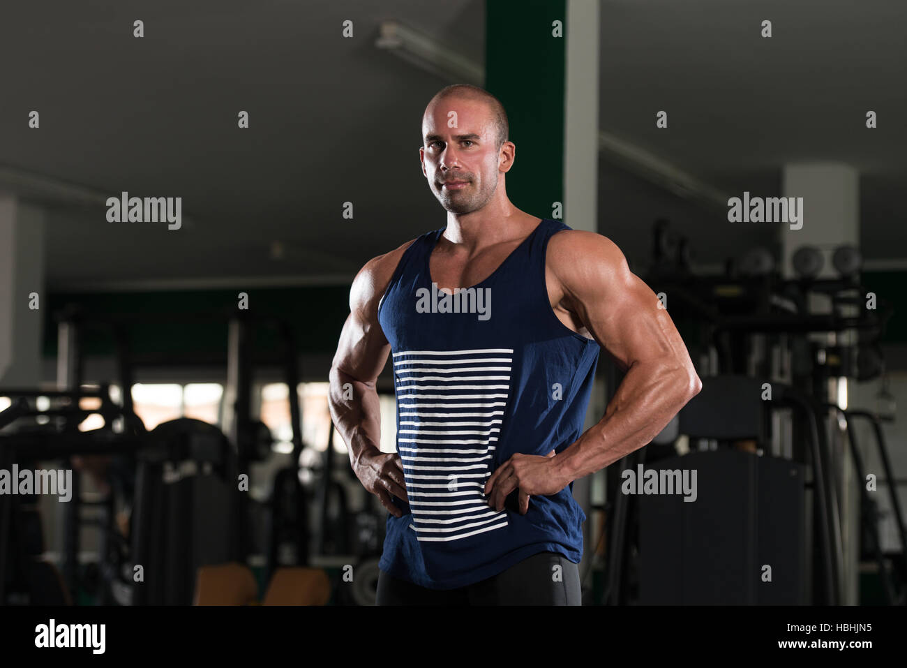 Young Bald Man Standing Strong In The Gym And Flexing Muscles ...