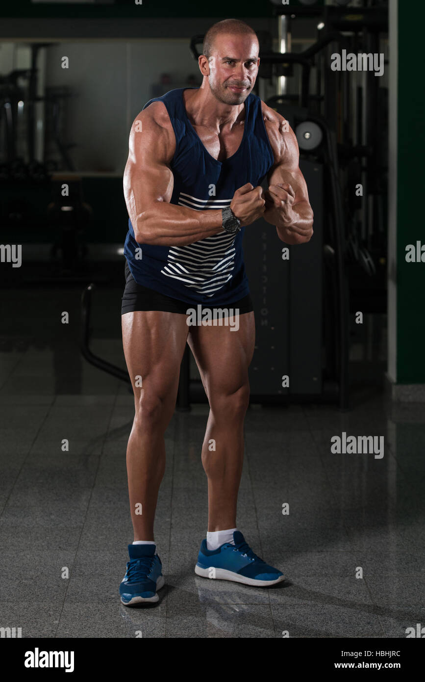 Young Bald Man Standing Strong In The Gym And Flexing Muscles ...