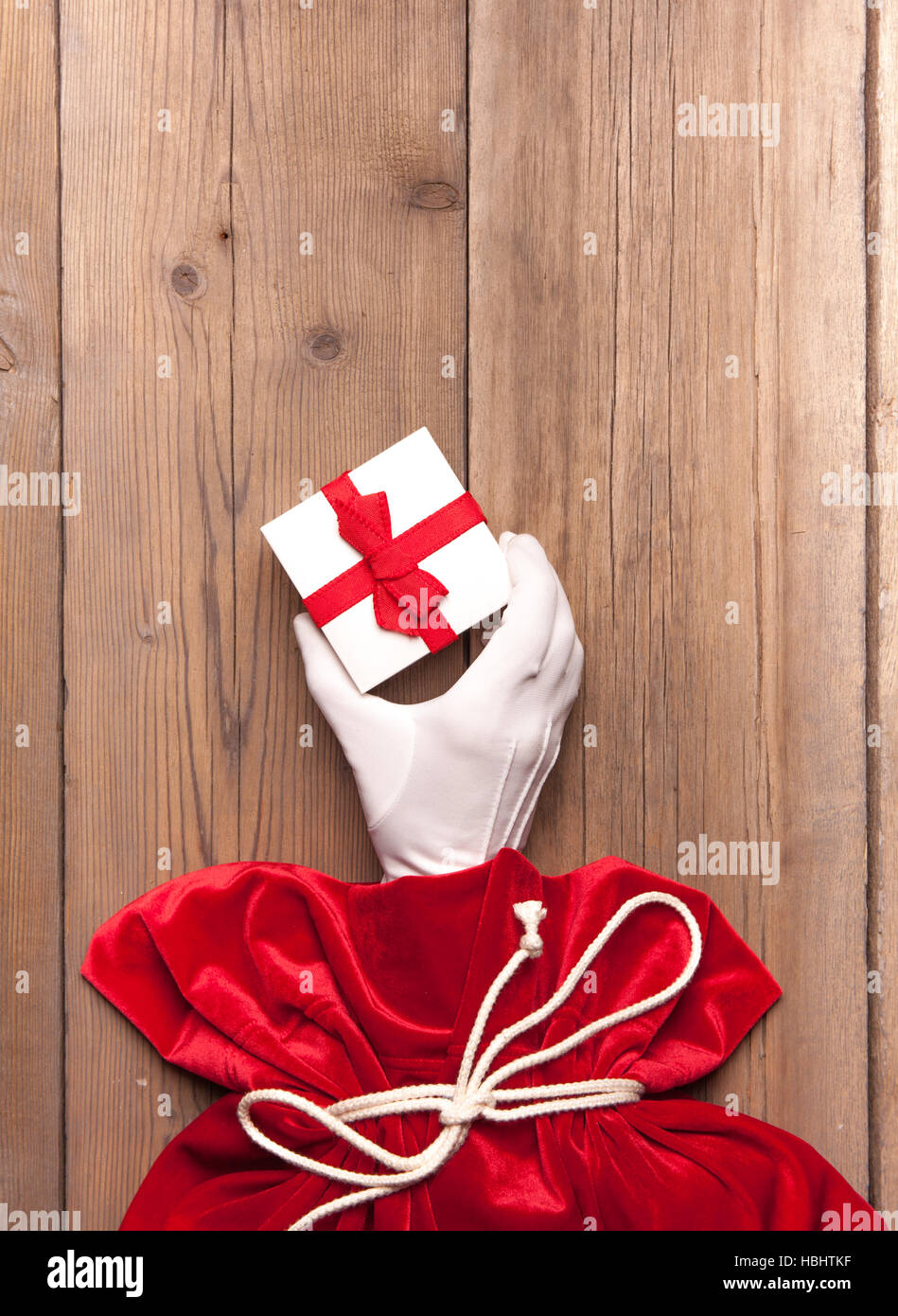 Santa Claus hand give a present from the red bag on Old Wooden ...