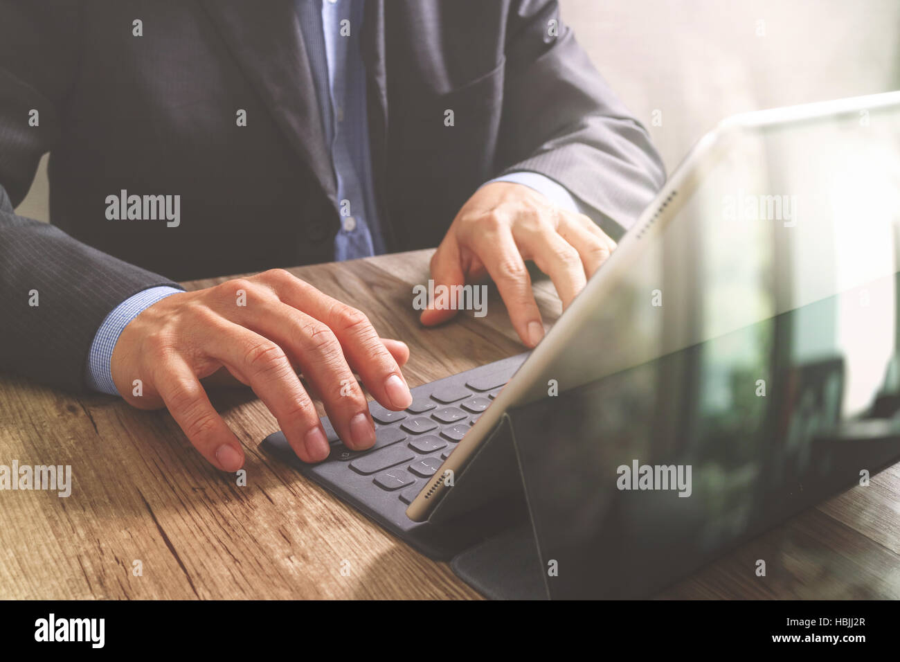 success businessman hand working with digital tablet docking smart keyboard on wooden desk ...