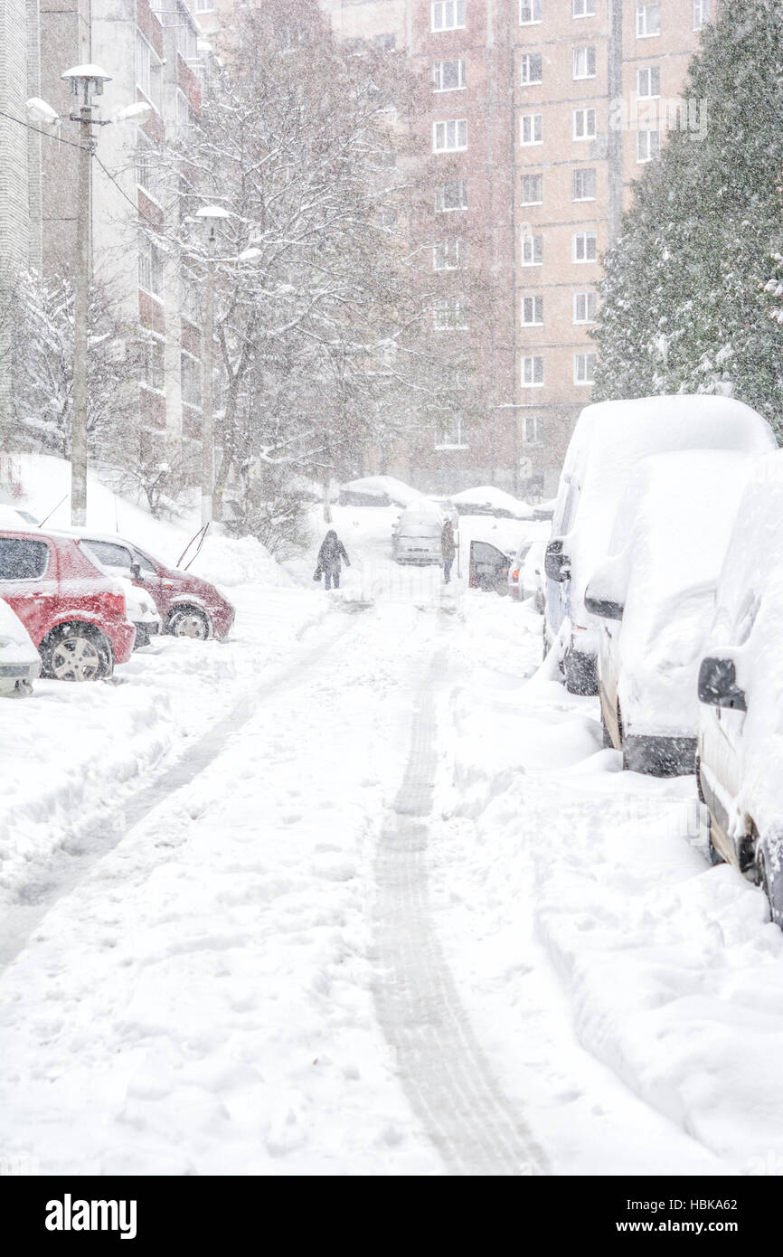 Snowstorm, snow-covered street and cars with a lonely pedestrian Stock ...