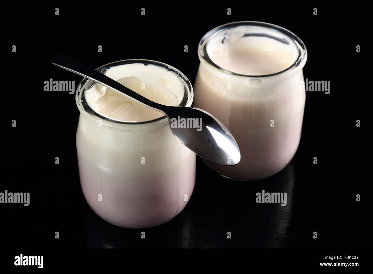 Yogurt in open small glass jar with spoon at black background Stock ...