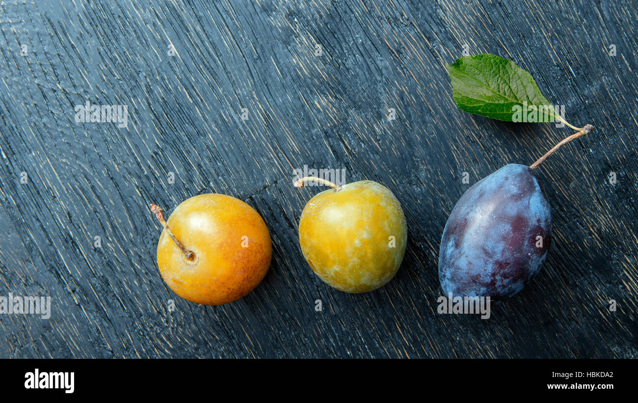 three plums on a black background Stock Photo - Alamy
