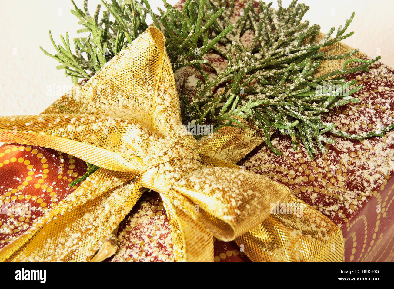 Snowy winter gift box with Golden bow and pine branch Stock Photo - Alamy