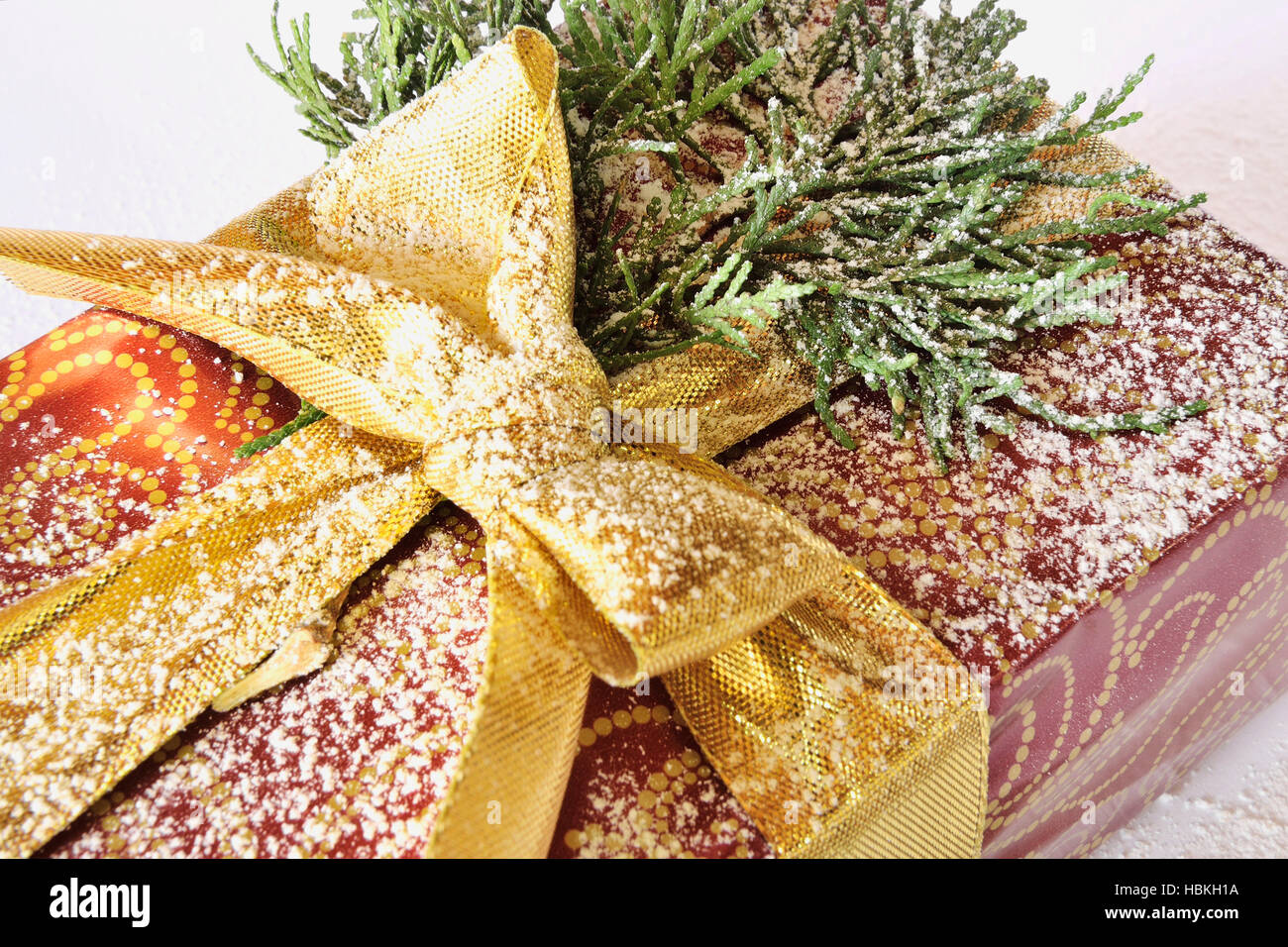 Snowy winter gift box with Golden bow and pine branch Stock Photo - Alamy