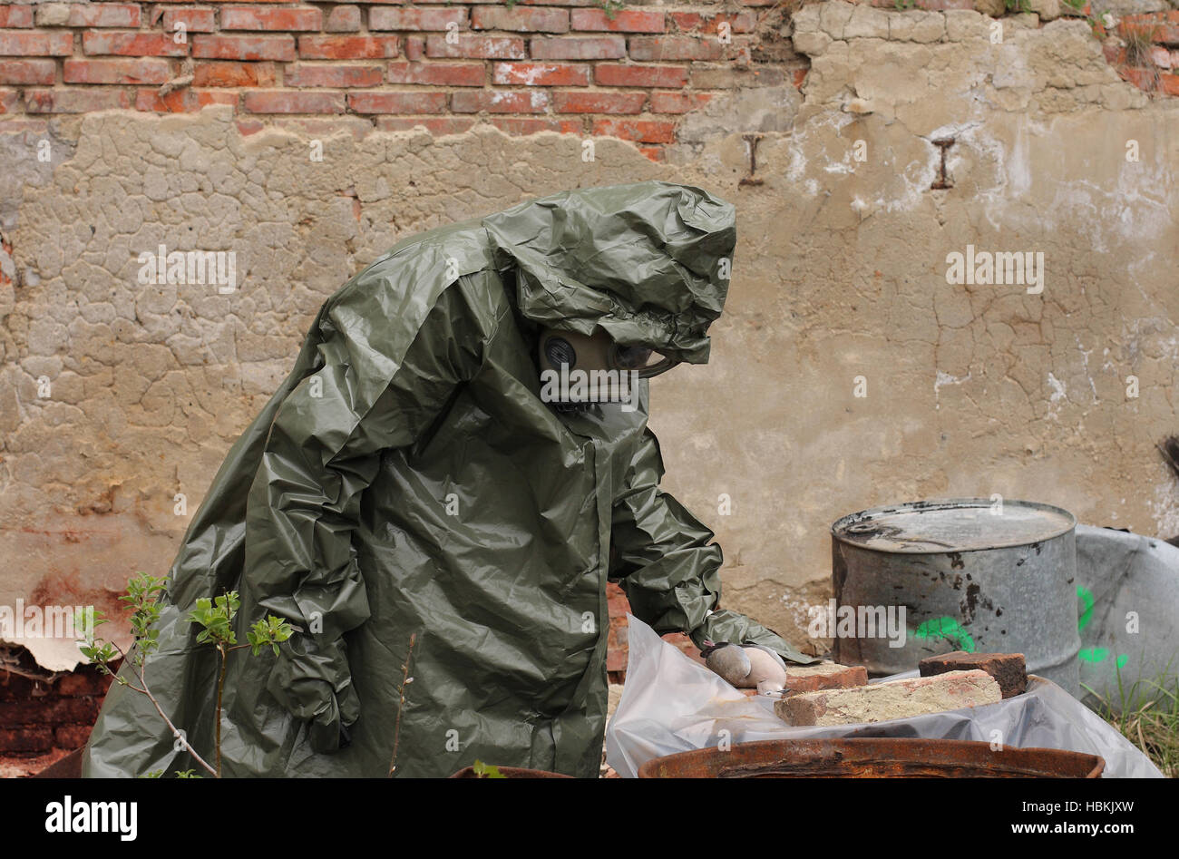 Man with gas mask and green military clothes explores dead bird after ...