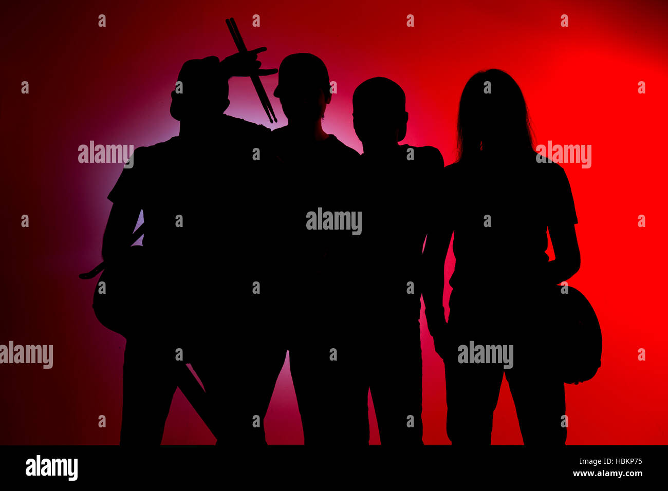 Band of young male musicians standing with instruments on a red ...