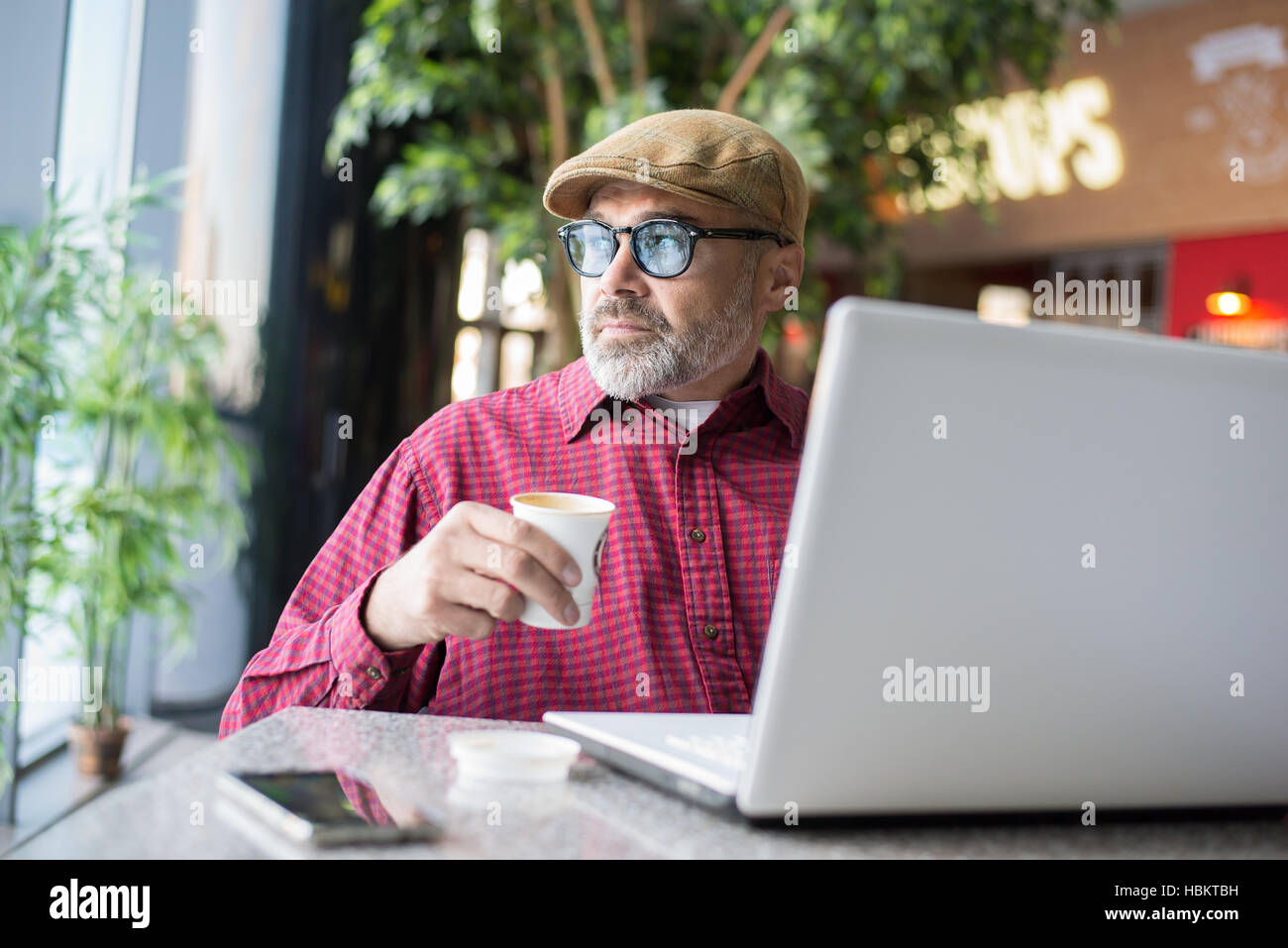 Adult Hipster man using computer in public place Stock Photo - Alamy