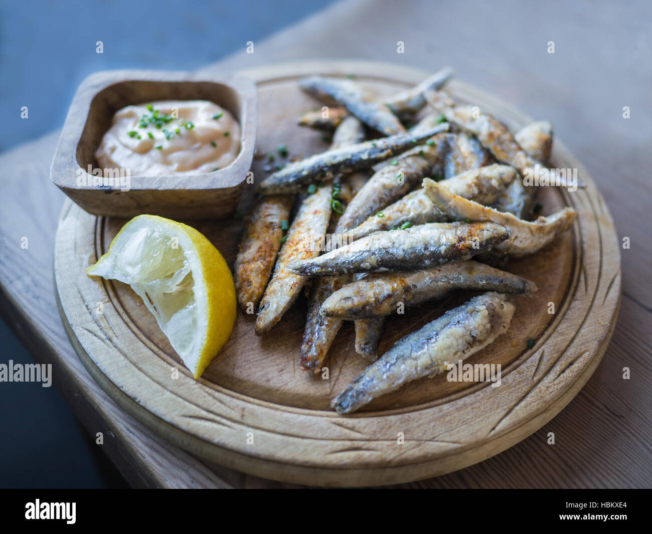 Whitebait, small fried fish served on a wooden rustic platter and ...