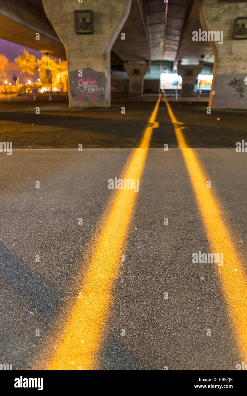 Lines of light from overhead bridges with people walking across them ...