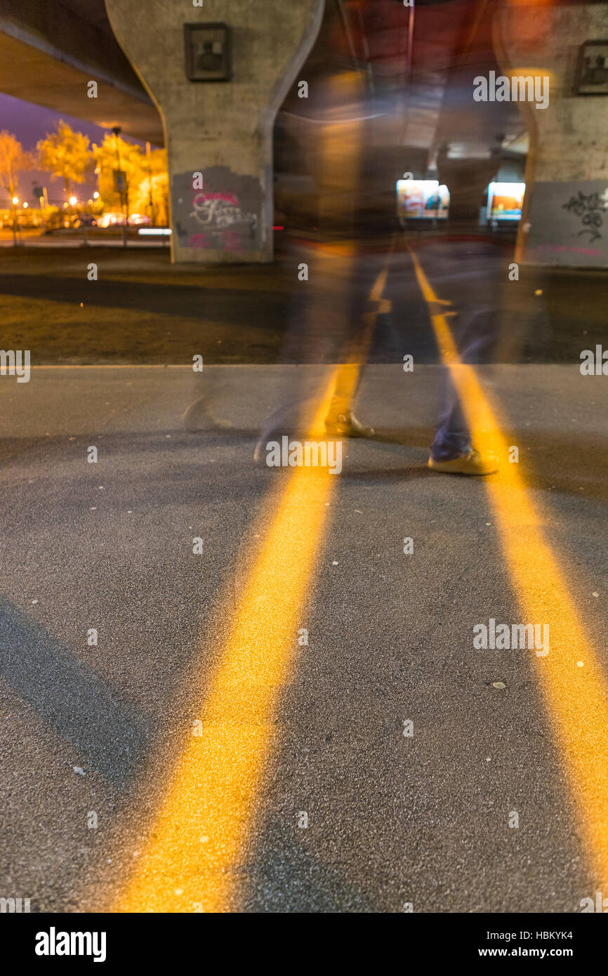 Lines of light from overhead bridges with people walking across them ...