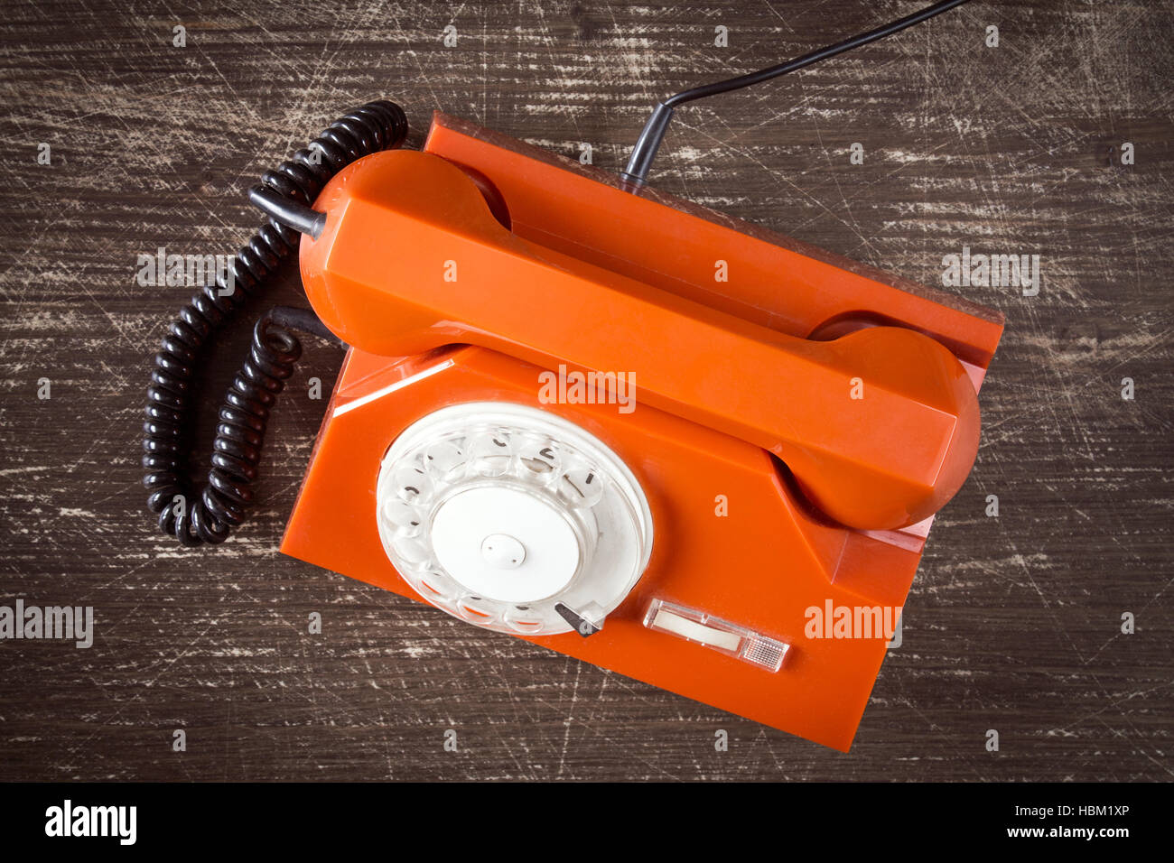 Old orange retro phone with rotary dial. Top view on wooden background ...