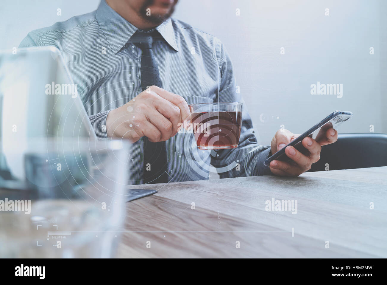 success businessman hand using smart phone,digital tablet docking smart keyboard,coffee cup on ...