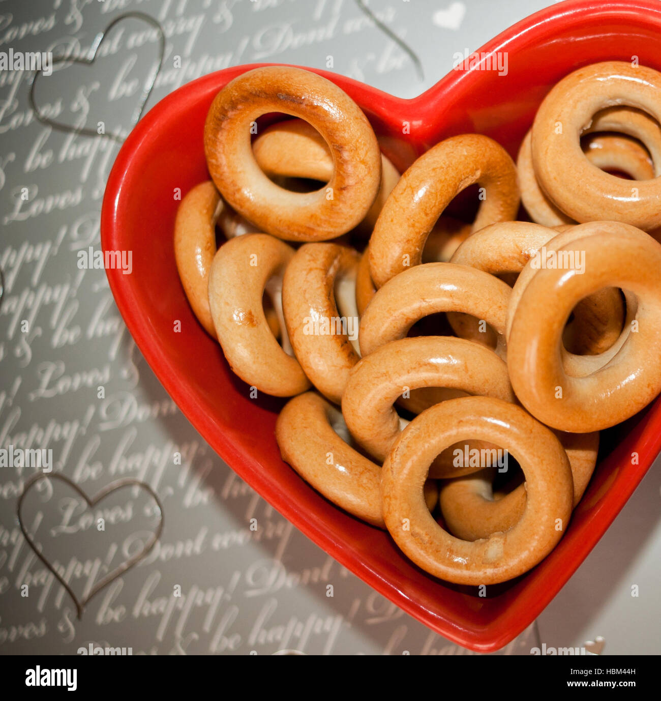 Тop view. Glazed bagels on red plate in shape of heart on gray words ...